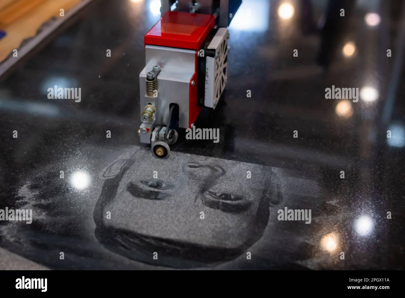 Stone engraving machine etching portrait on black granite gravestone ...