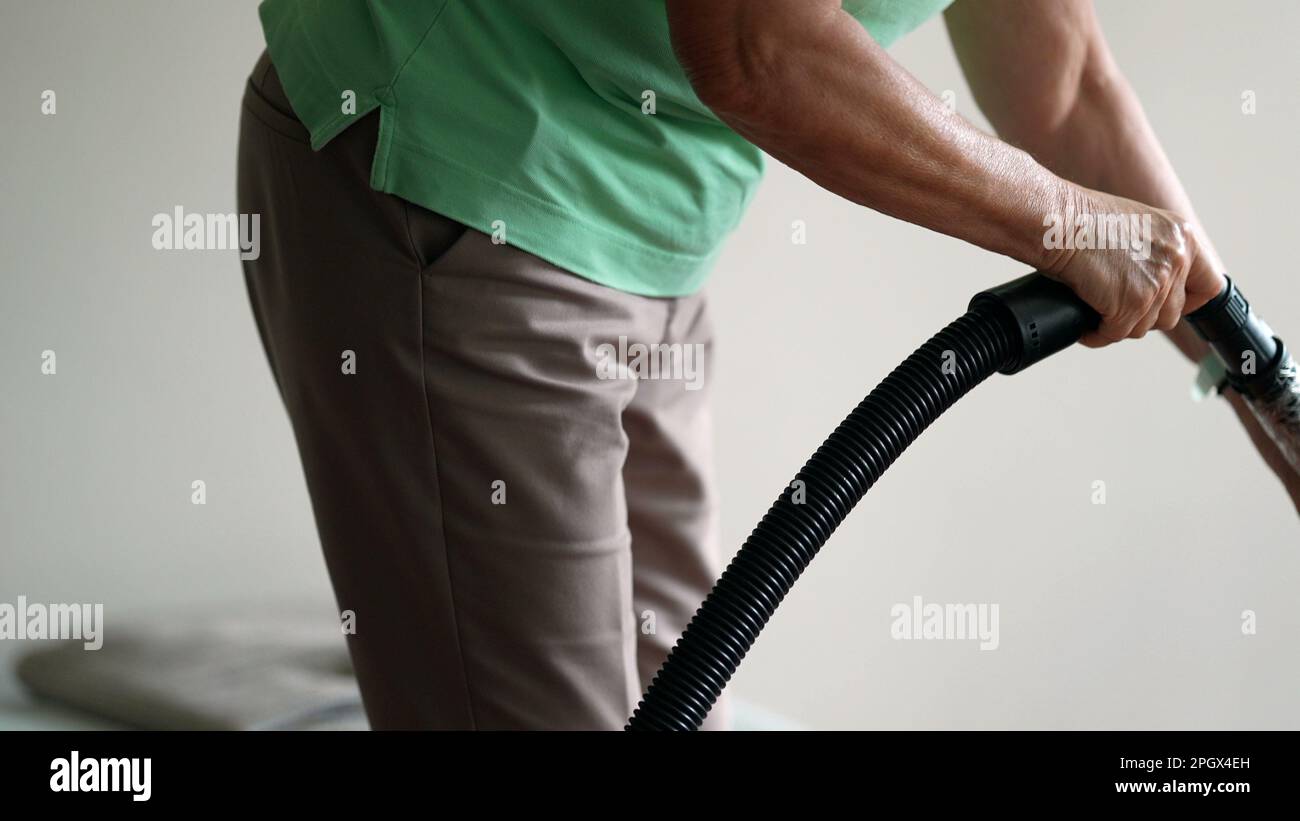 One mature woman doing domestic chores vacuuming room floor with vacuum ...