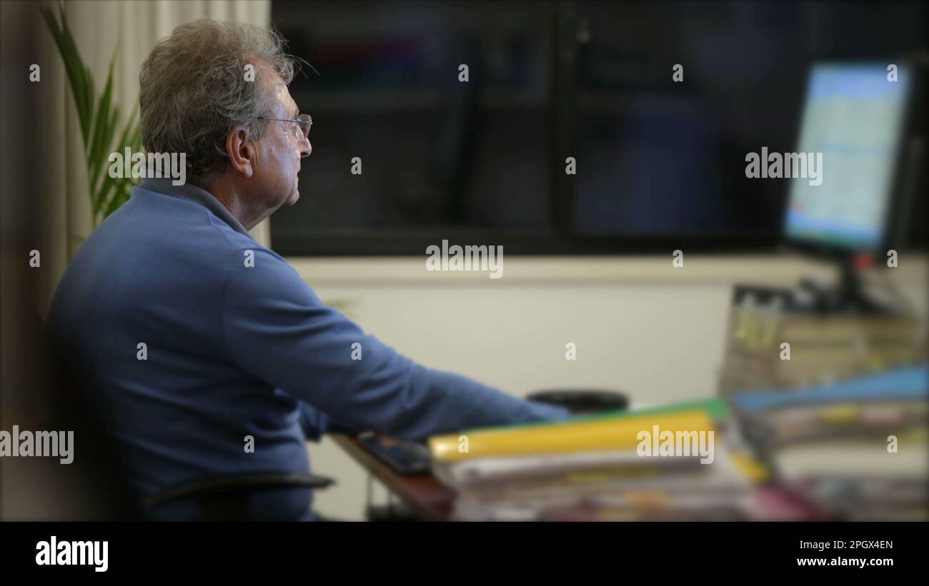Candid senior man working at night in front of computer screen. One ...