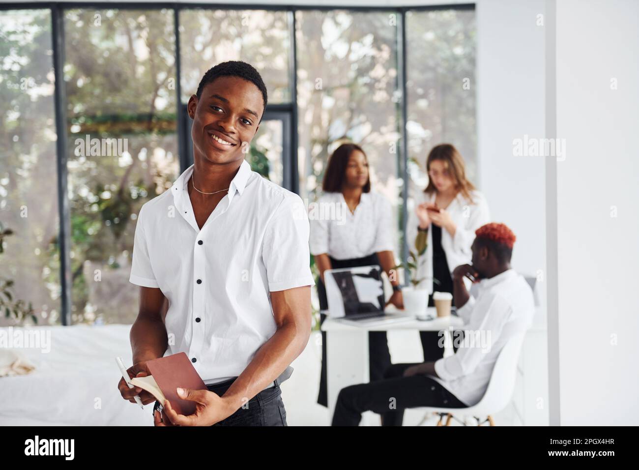 Positive guy standing in front of his colleagues. Group of african ...