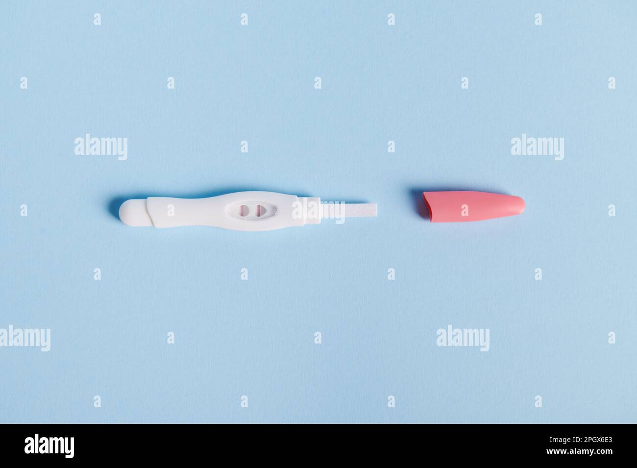 Isolated shot of positive pregnancy test kit with two strips on blue ...