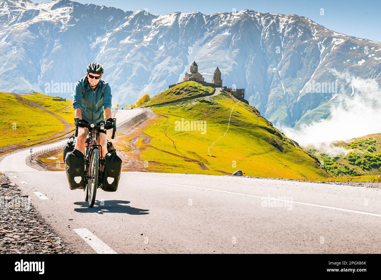 Cyclist back view on the road in scenic caucasus nature with Gergeti ...
