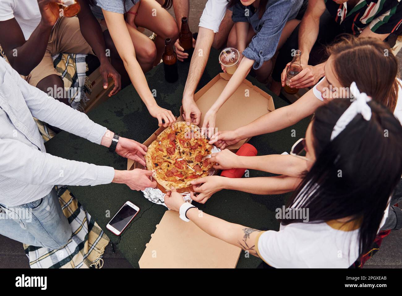 With delicious pizza. Group of young people in casual clothes have a ...