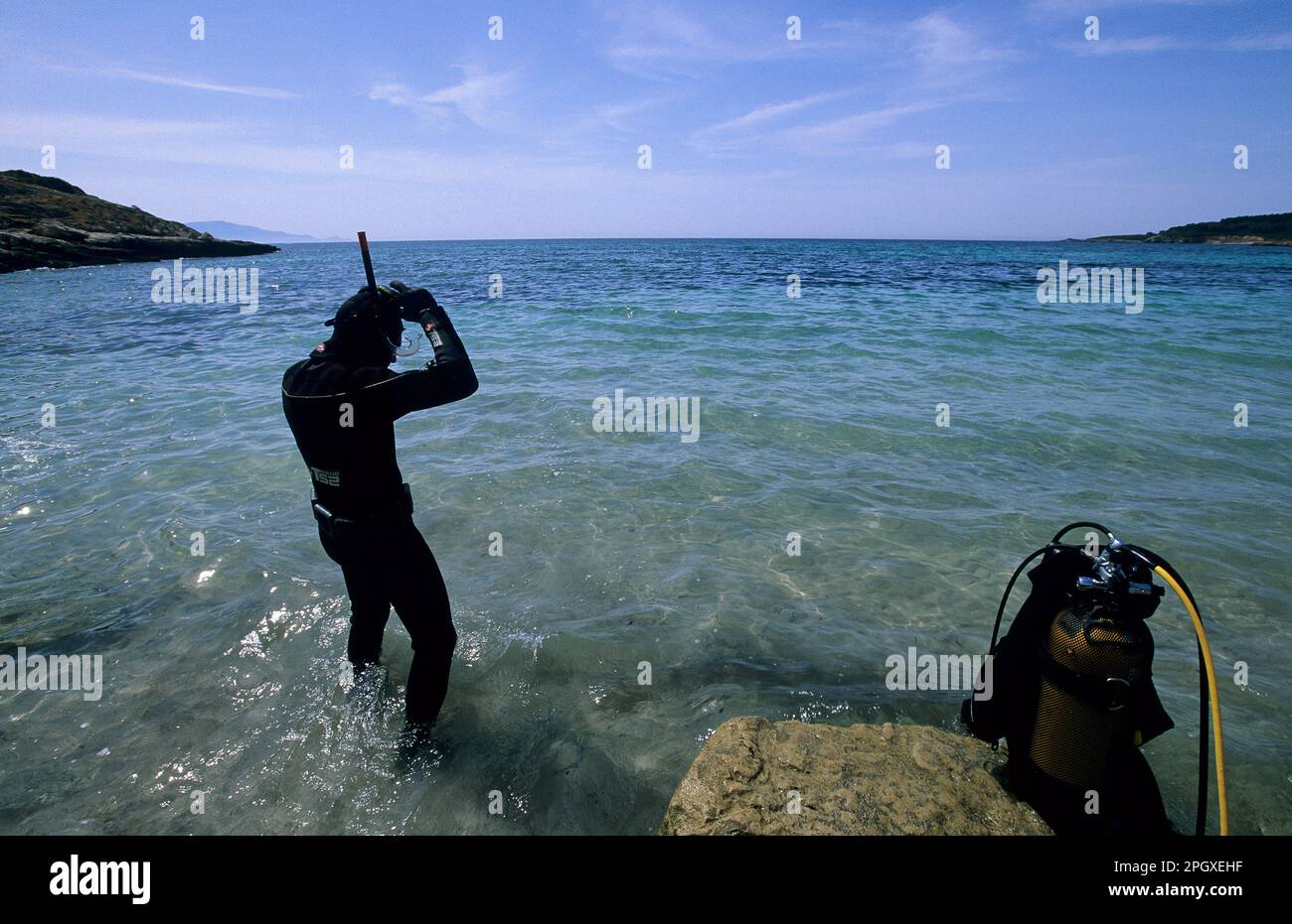 . A diver preparing himself for a dive from a beach. Alghero. Sardinia ...