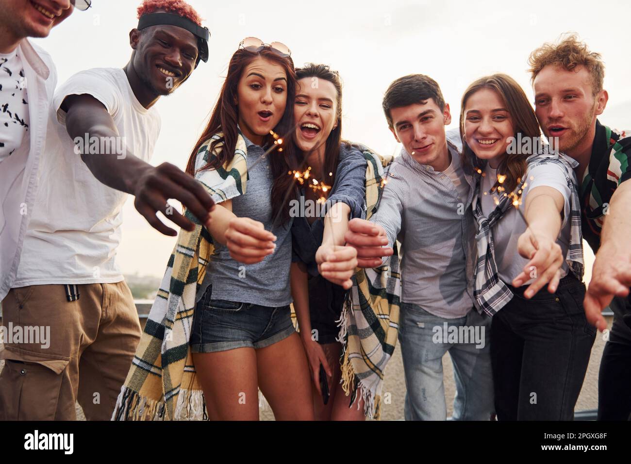 With sparklers in hands. Group of young people in casual clothes have a ...