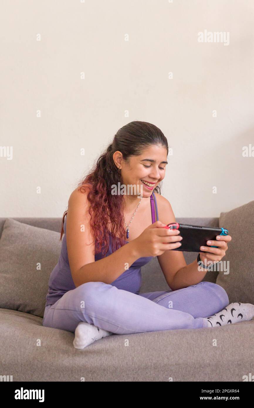 Latin woman playing happy game portable console. generation z gamer with controller. venezuelan ...