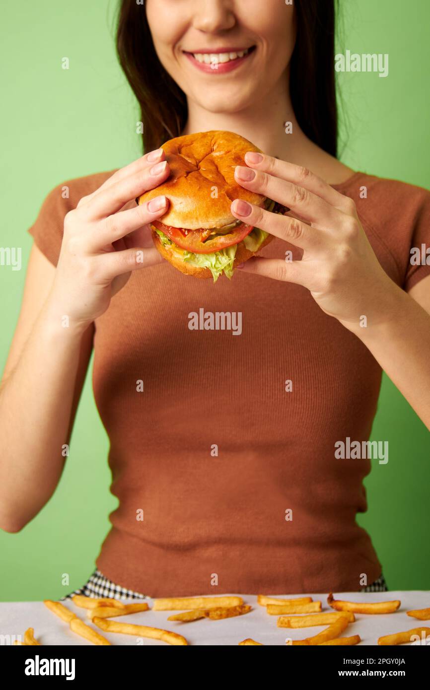 Portrait of woman smiling whle holding a hamburger cheeseburger with ...