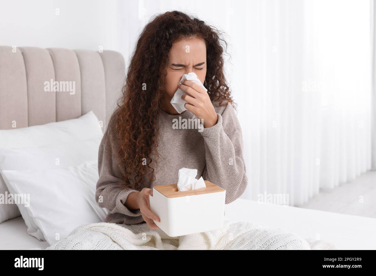 Sick African American woman with box of paper tissues suffering from ...