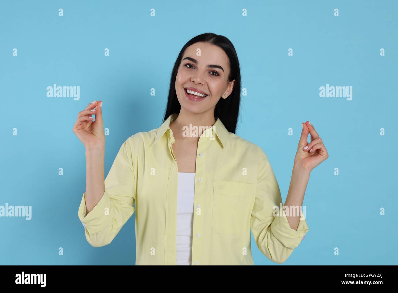 Young woman snapping fingers on light blue background Stock Photo - Alamy