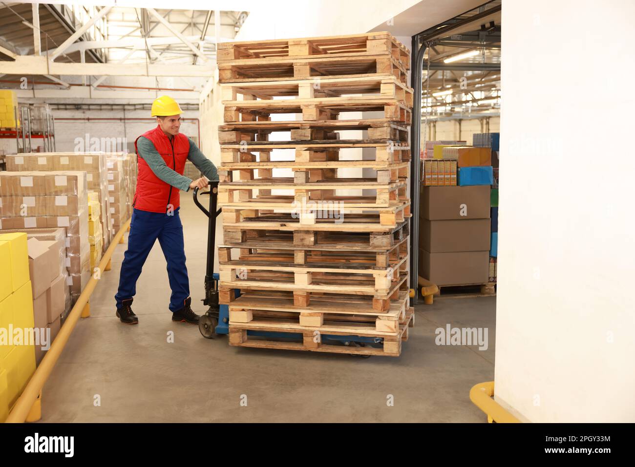 Worker moving wooden pallets with manual forklift in warehouse Stock ...