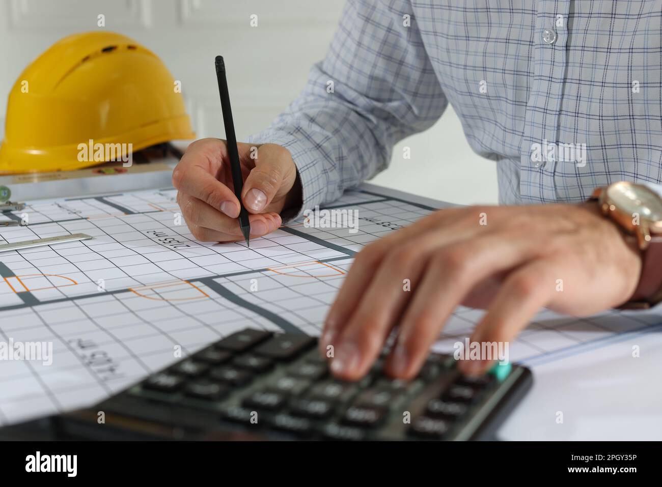 Architect working with construction drawings and calculator indoors ...