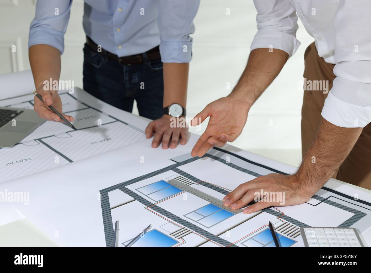 Architects working with construction drawings at table in office, closeup Stock Photo - Alamy