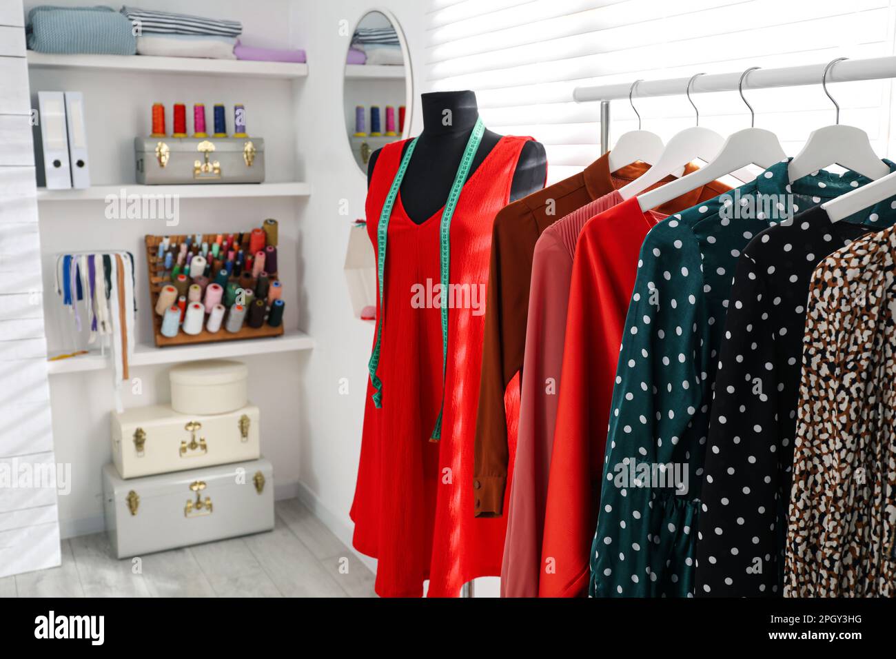 Dressmaking workshop interior with stylish female clothes and mannequin ...