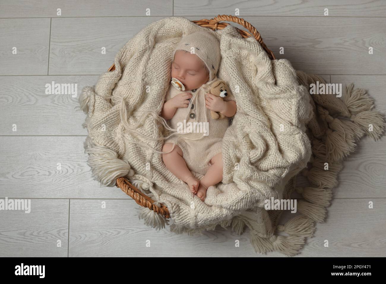 Adorable newborn baby with pacifier and toy bear sleeping in wicker ...