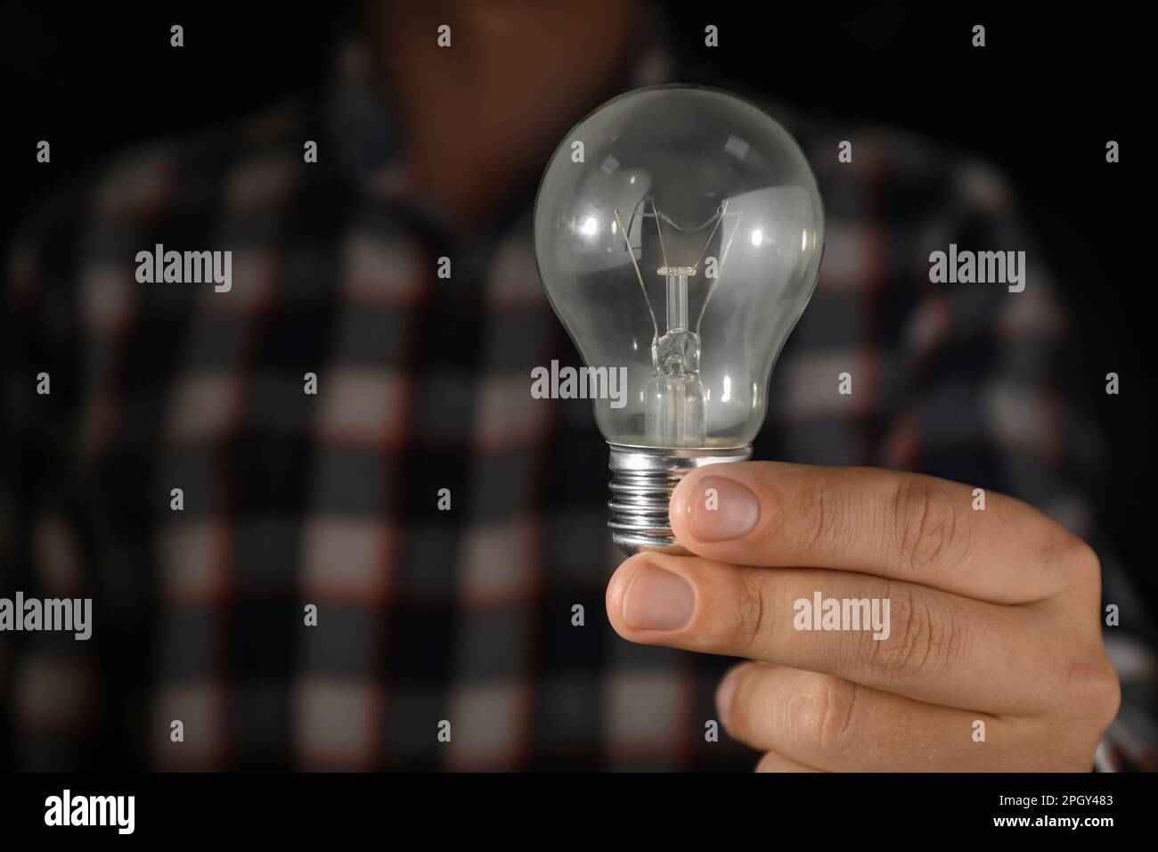 Man holding incandescent light bulb on dark background, closeup. Space for text Stock Photo - Alamy