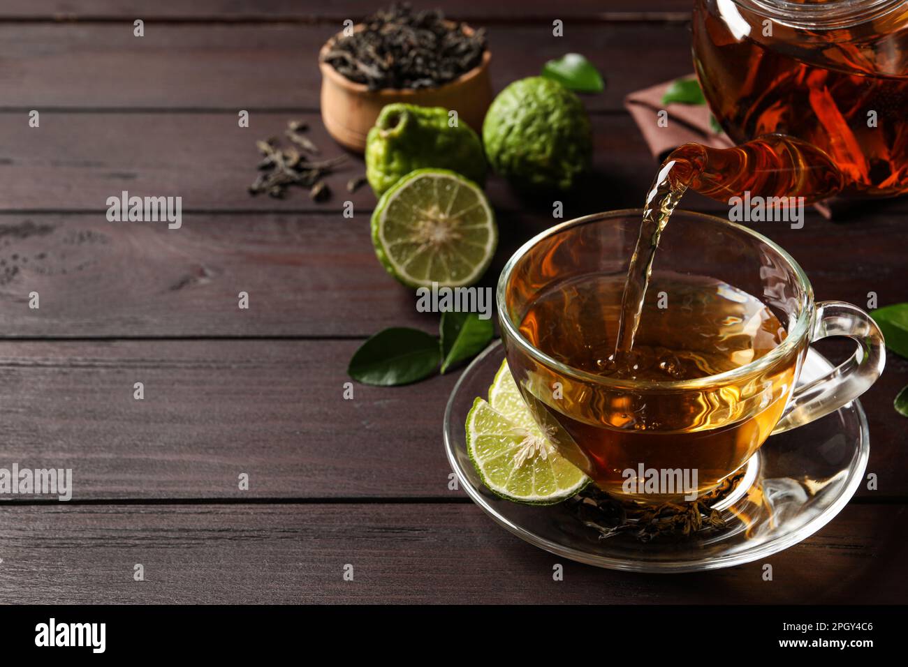 Pouring bergamot tea into glass cup at wooden table. Space for text ...