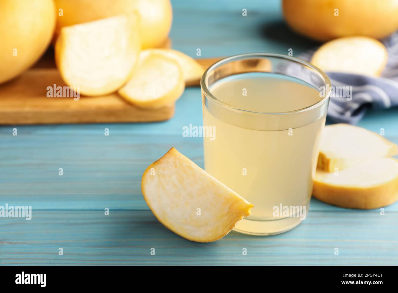 Glass of freshly made turnip juice on turquoise wooden table. Space for ...