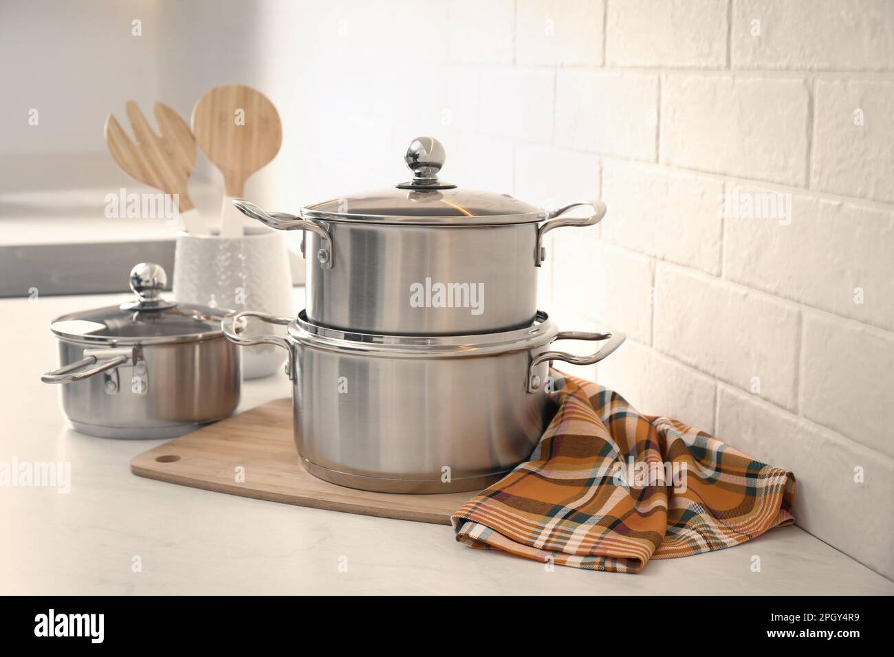 Set of stainless steel cookware and kitchen utensils on table near ...