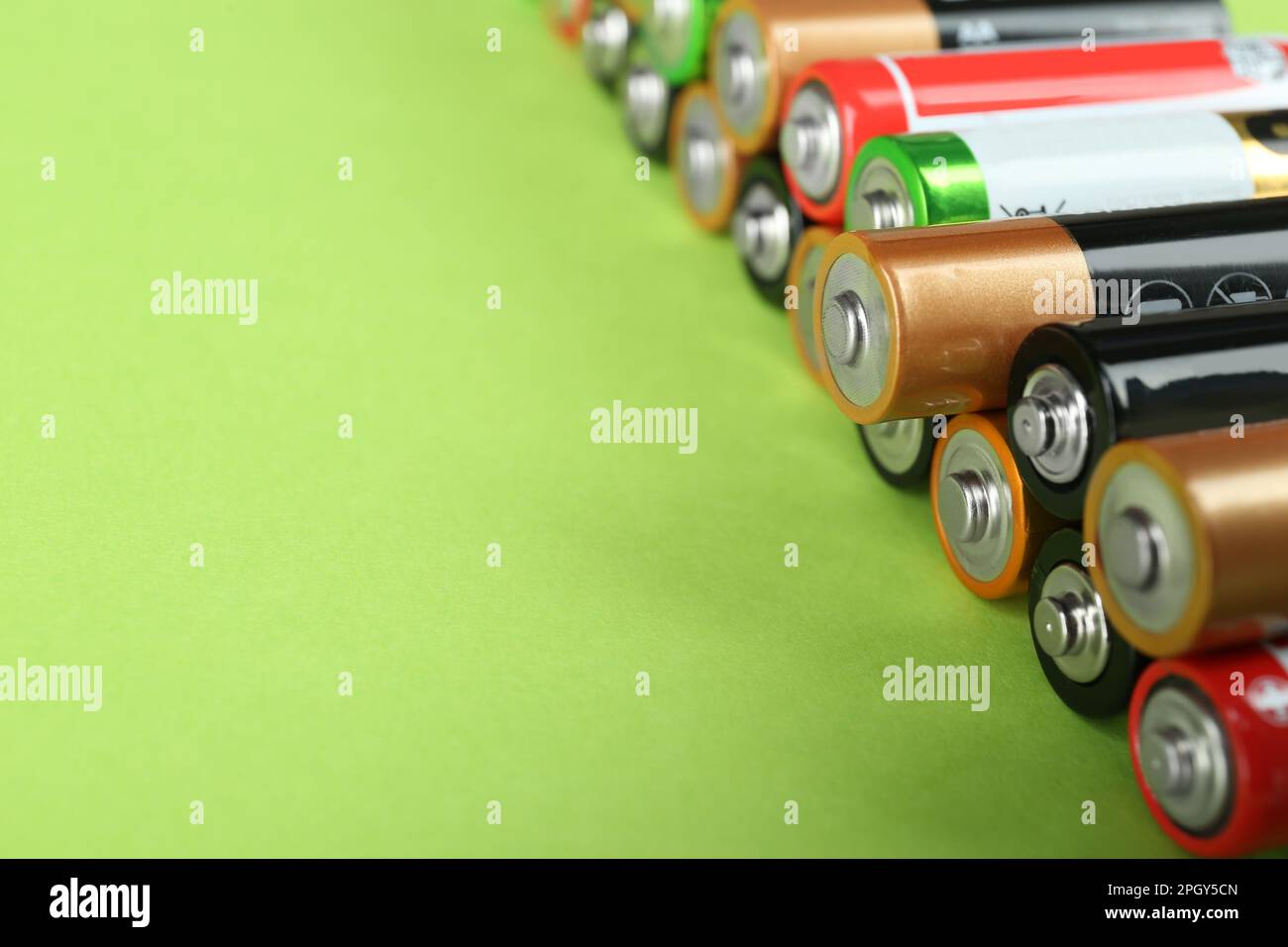New AA batteries on light green background, closeup. Space for text ...