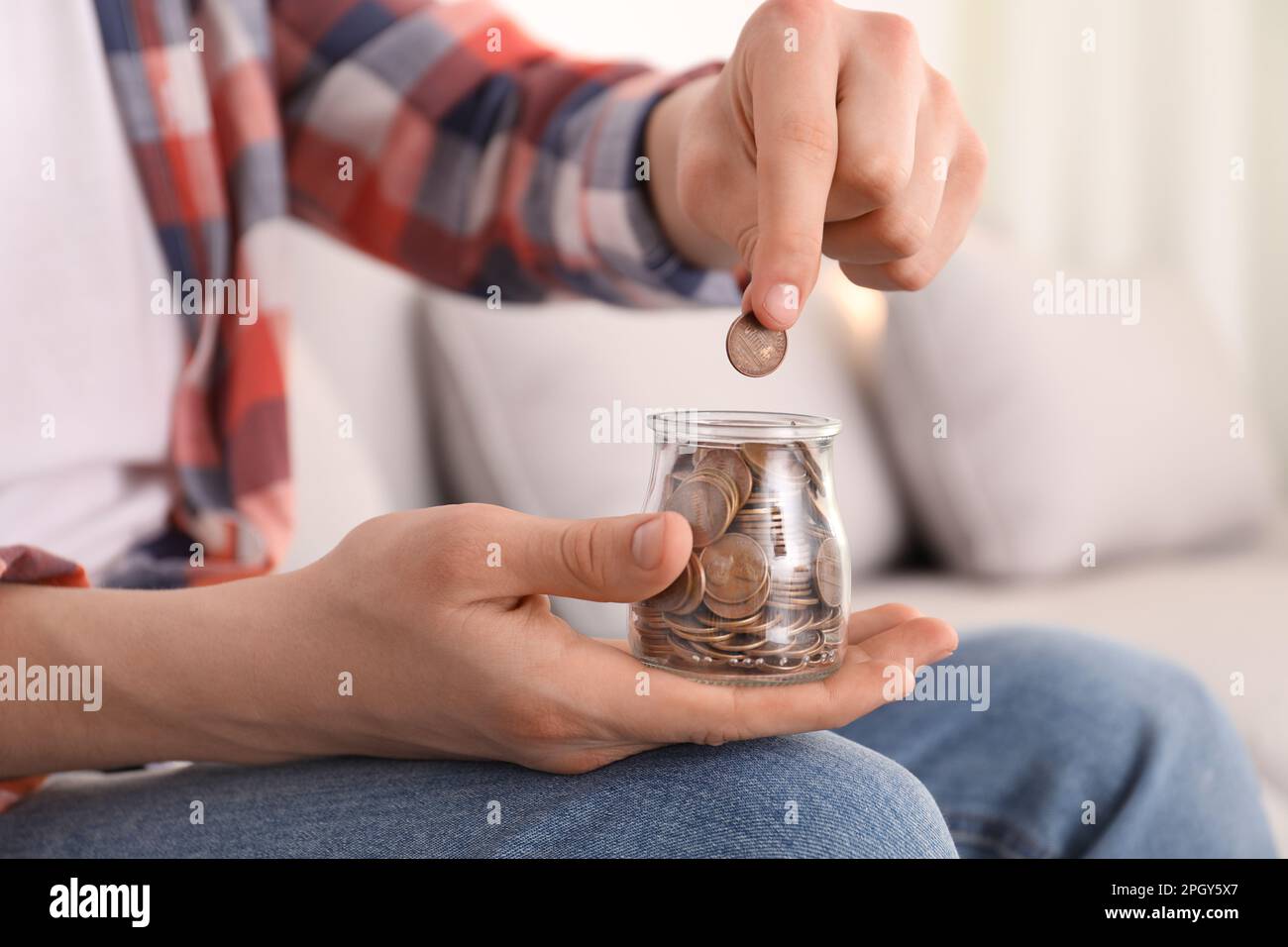 Hand putting coin glass jar hi-res stock photography and images - Alamy