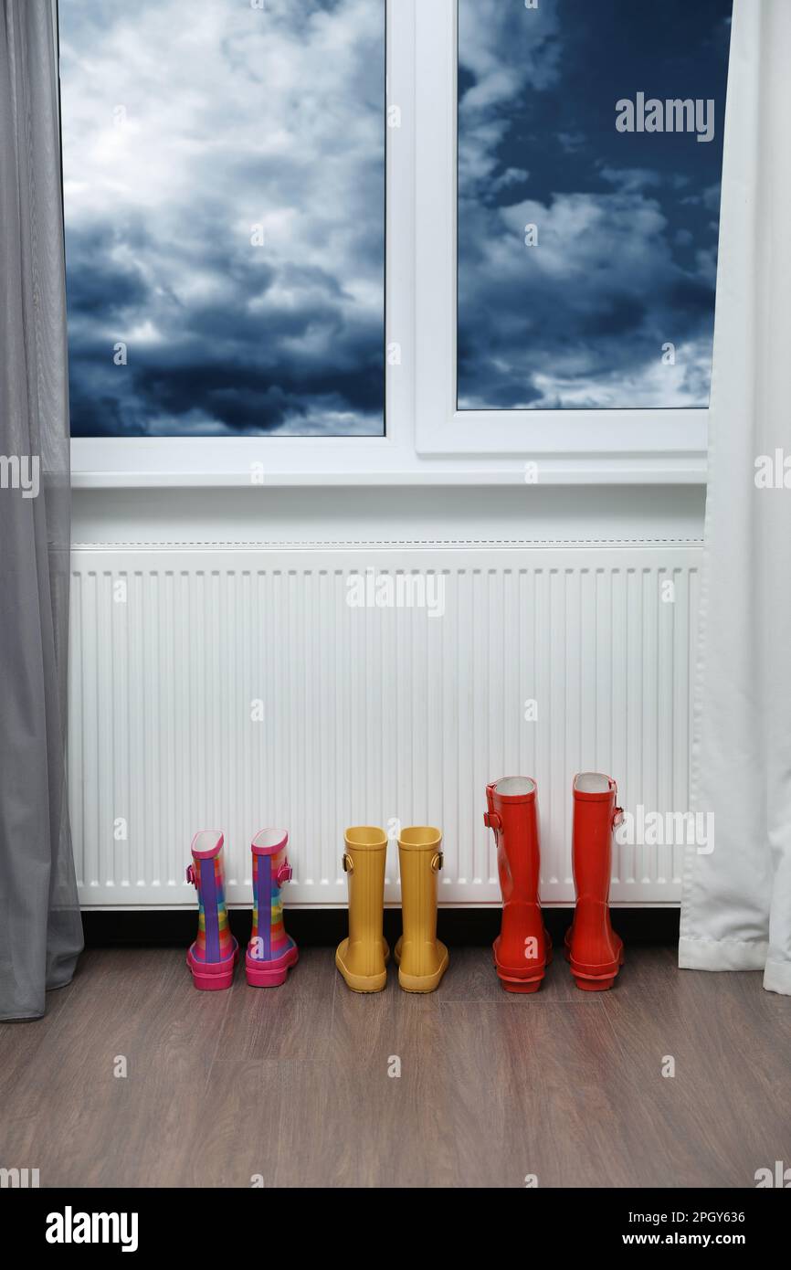 Rubber boots near heating radiator in room Stock Photo - Alamy