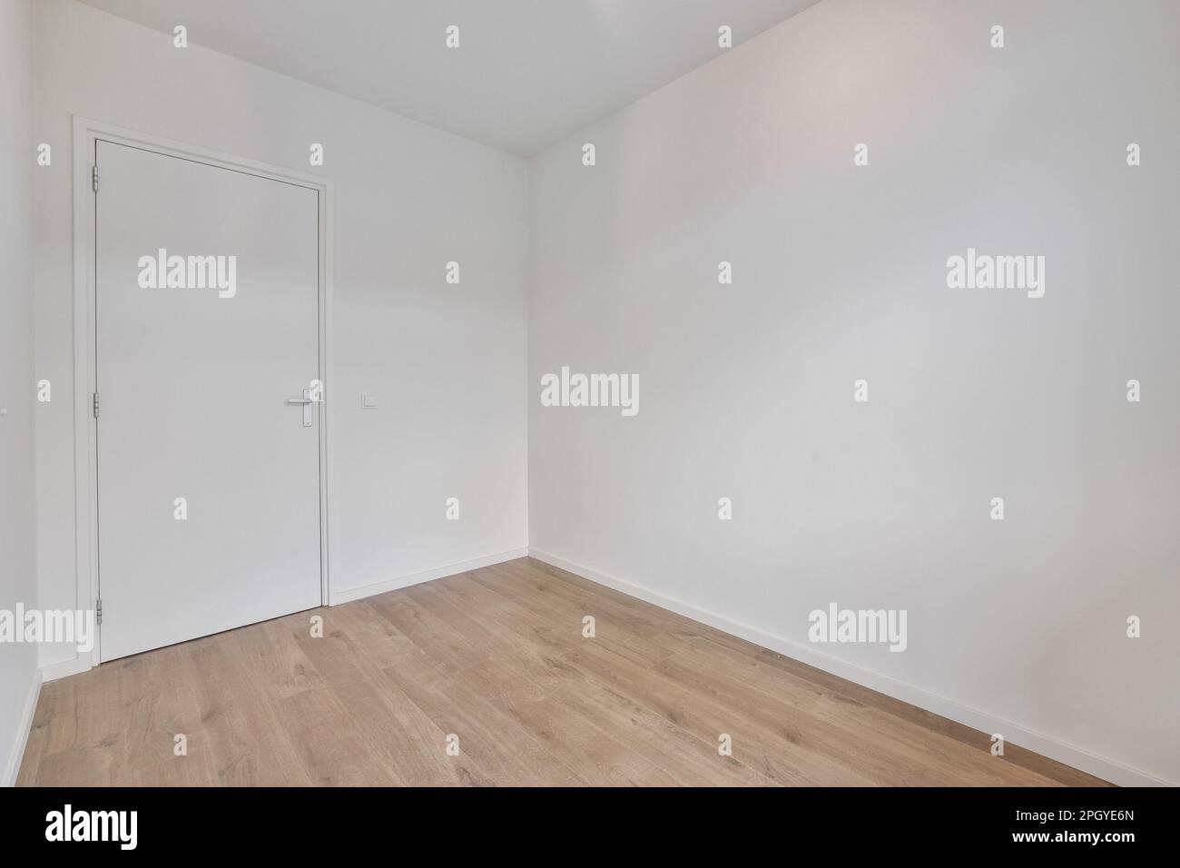 an empty room with wood floors and white walls, there is a door leading ...