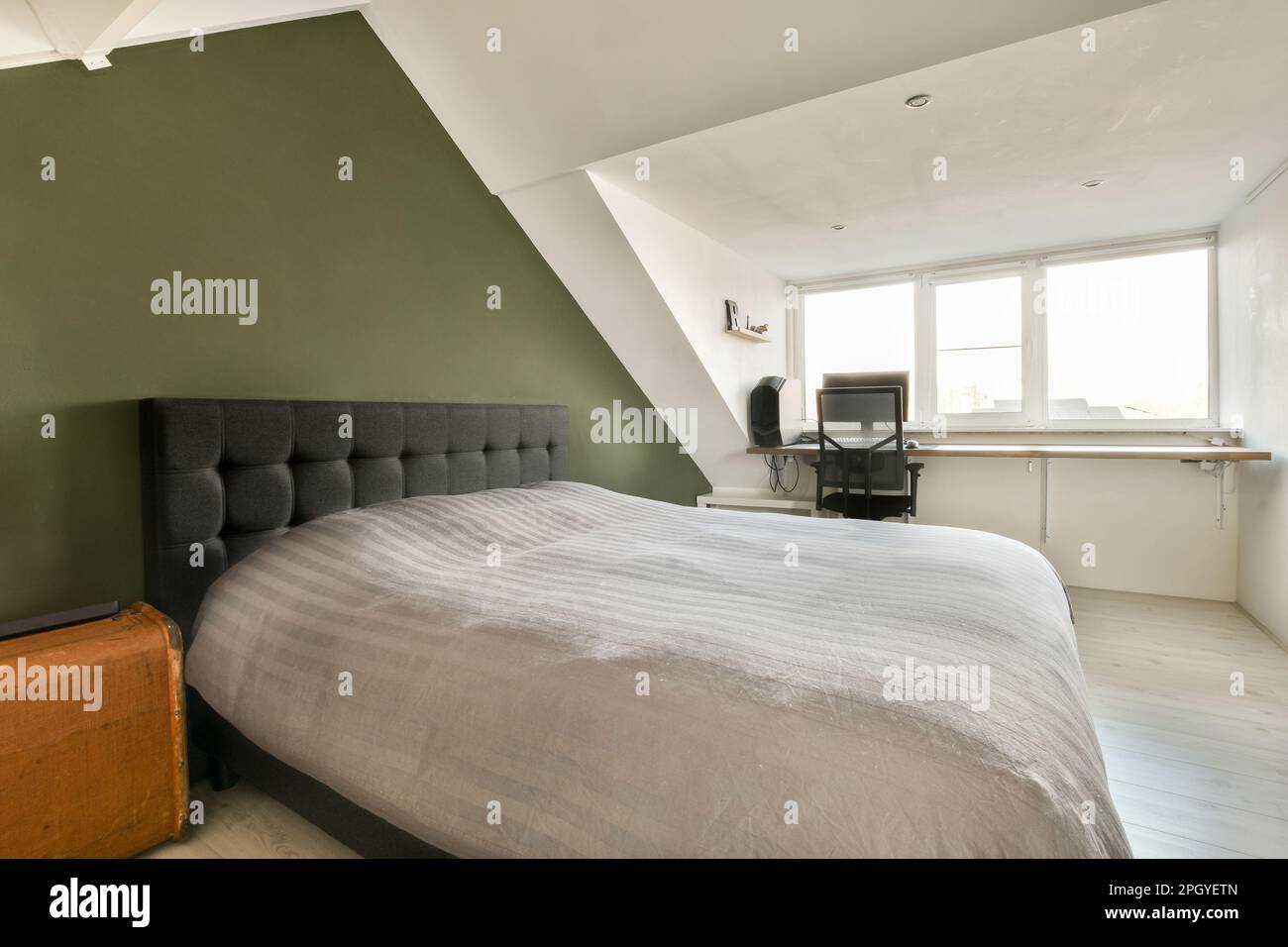 a bedroom with a bed, desk and computer on the wall in front of the bed ...