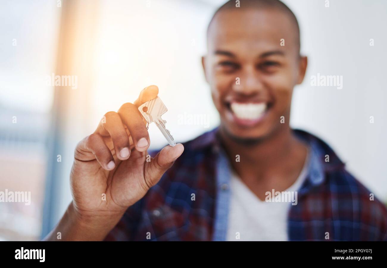 Life starts here. a handsome young man holding house keys in his new ...