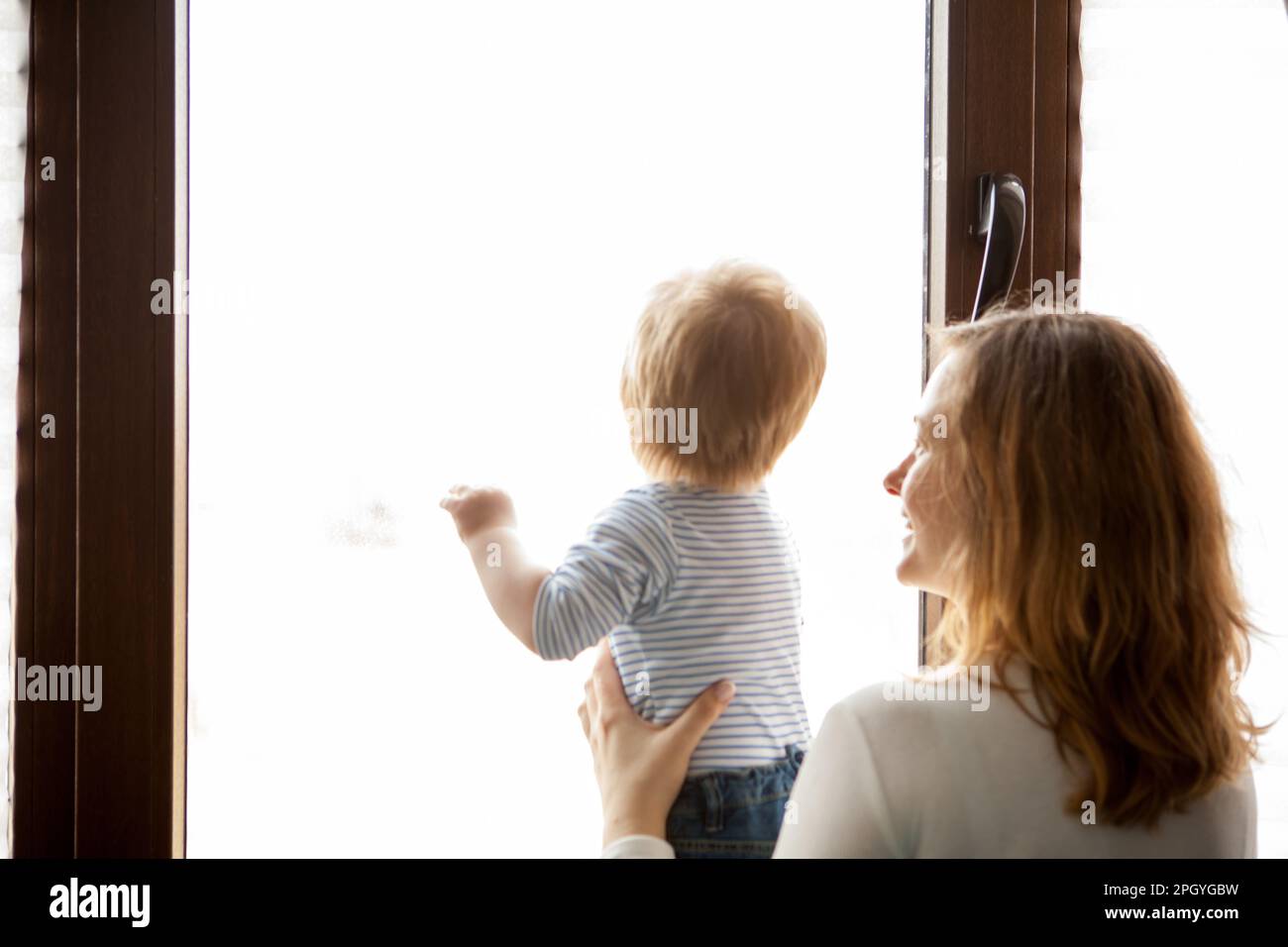 Mother with her baby child looking at the window. Happy childhood and ...