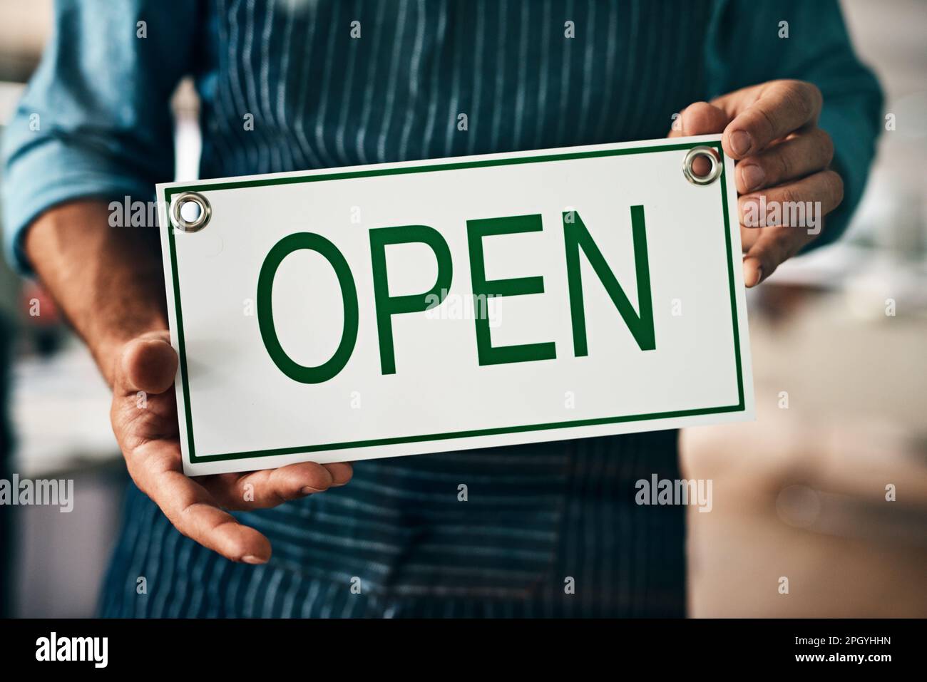 Please come in. a man holding up an open sign in his store Stock Photo ...