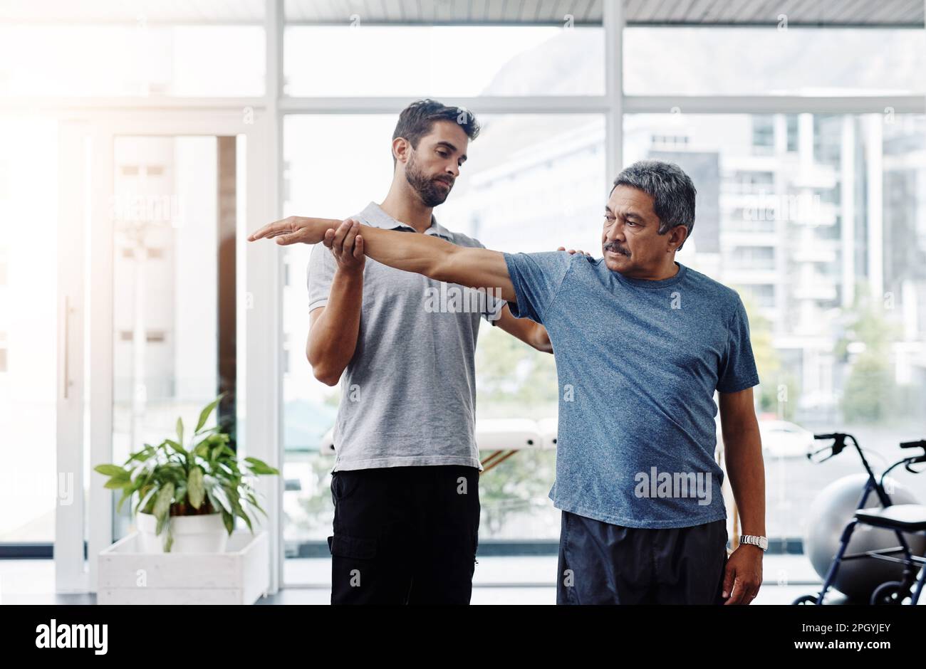 Hold it there as long as you can. a young male physiotherapist helping ...