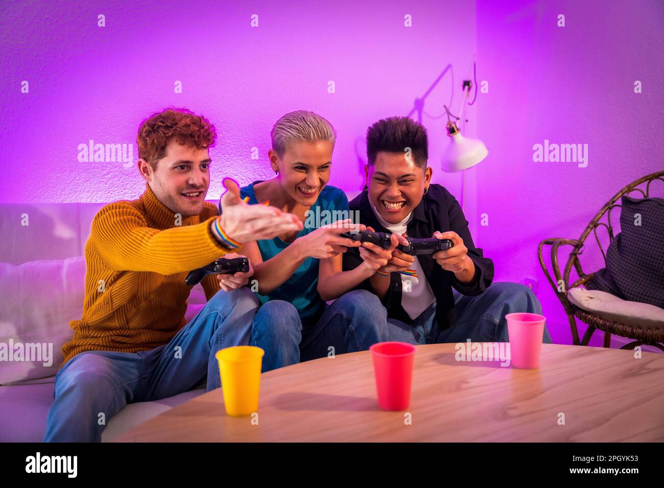 Group of young friends play video games together on the sofa at home ...