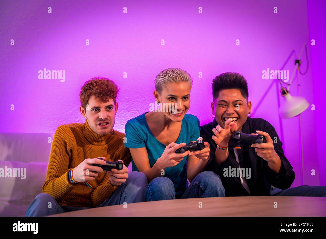 Group of young friends playing video games together on the sofa at home ...