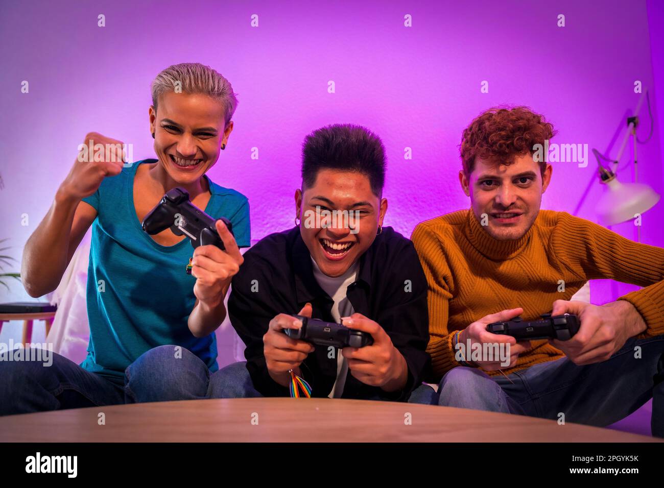 Group of young friends playing video games together on the sofa at home ...