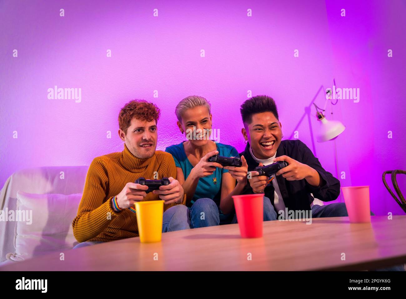 Group of young friends playing video games together on the sofa at home ...