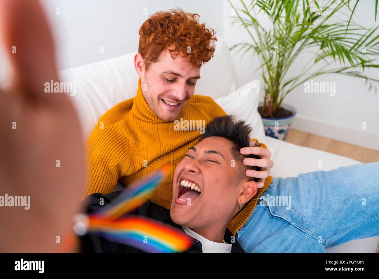 Beautiful gay couple being romantic indoors at home on the sofa, gay ...