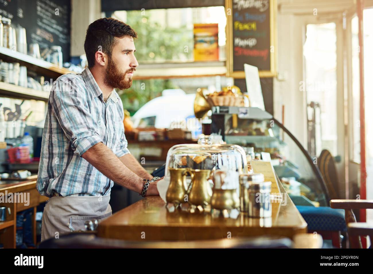 Waiting for the first customer to walk in. a young man working in a ...