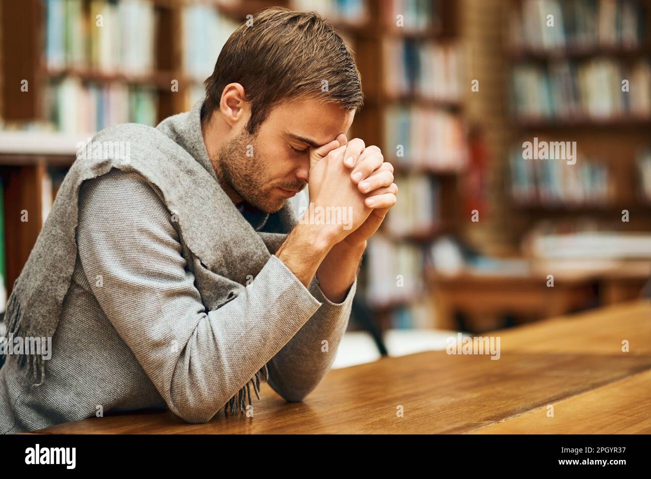 Seeking help from above. a handsome young man praying for help with his ...