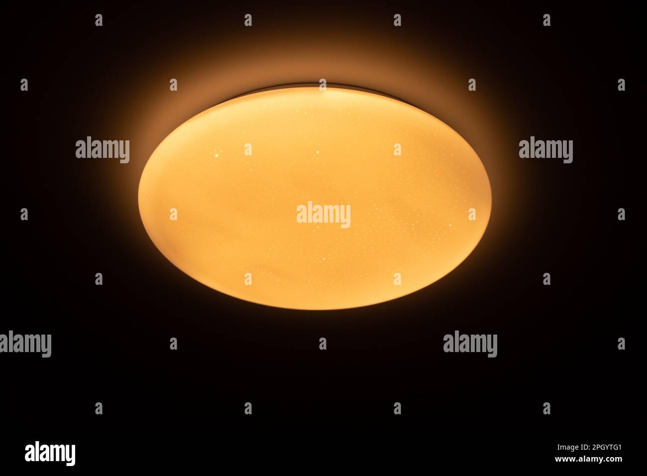 round flat chandelier on the dark ceiling of the house shines with ...