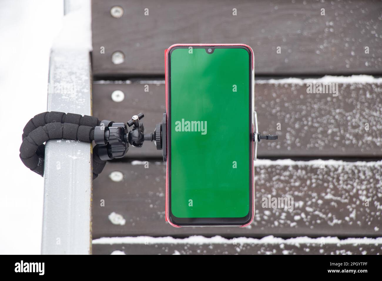 a mobile phone with a green screen fixed on a flexible stand on the ...