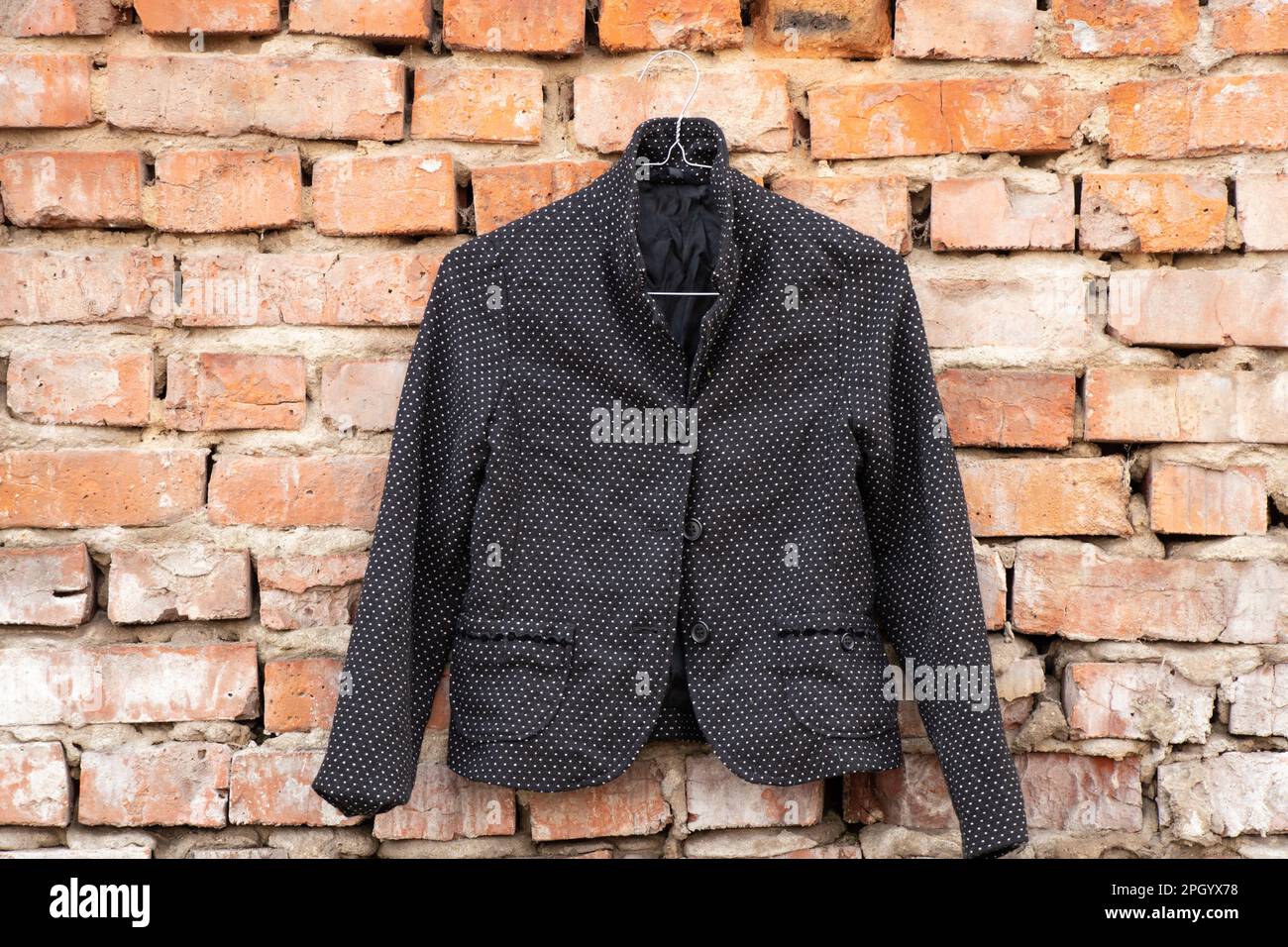 black womens blazer with polka dots hanging on a brick old wall outside ...