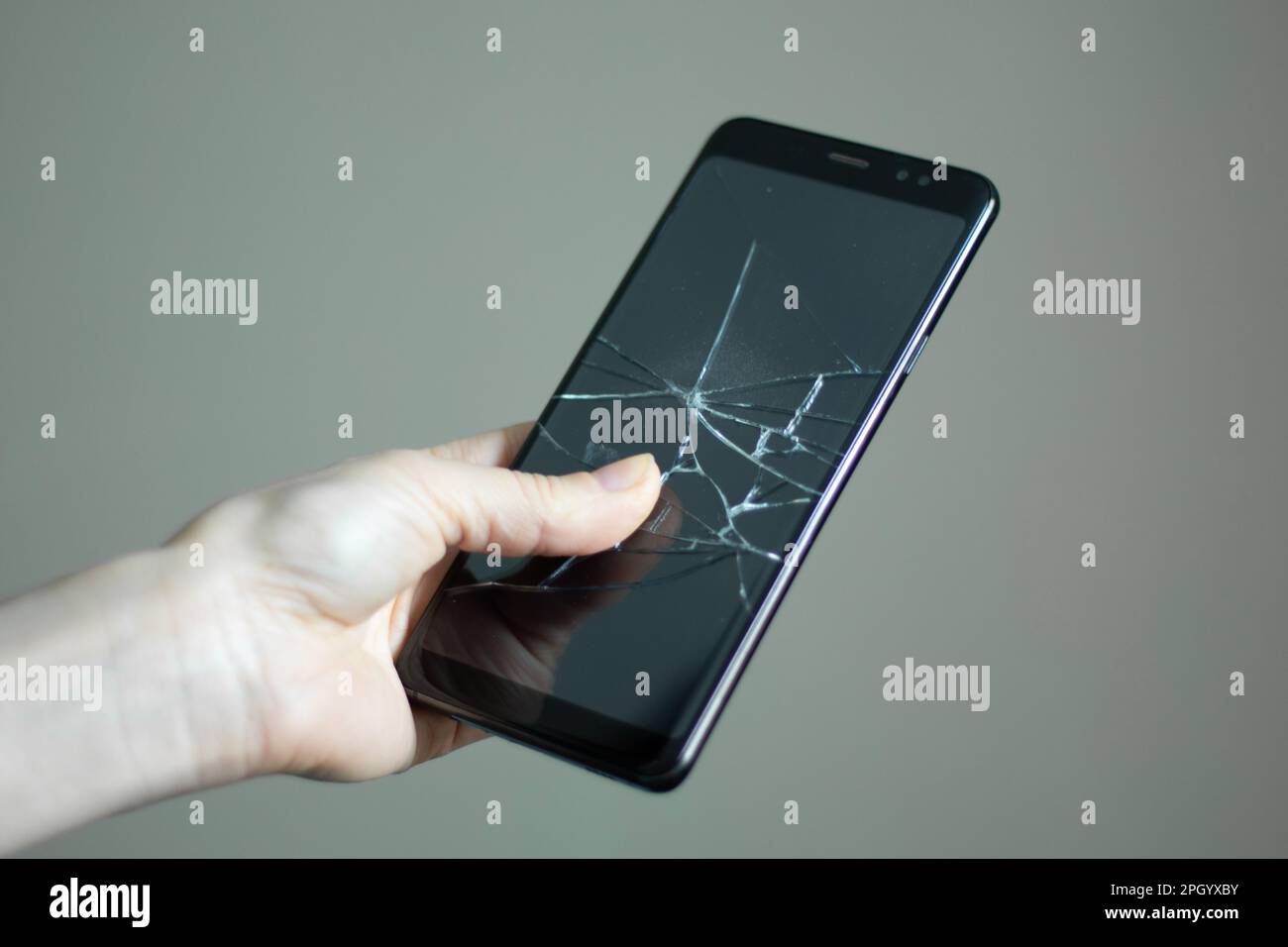 black touchscreen phone with a broken screen in the girl's hand close ...