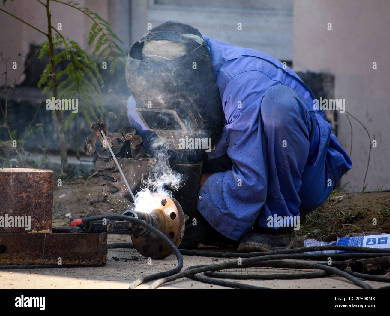 A welder welding wearing blue jacket Stock Photo - Alamy