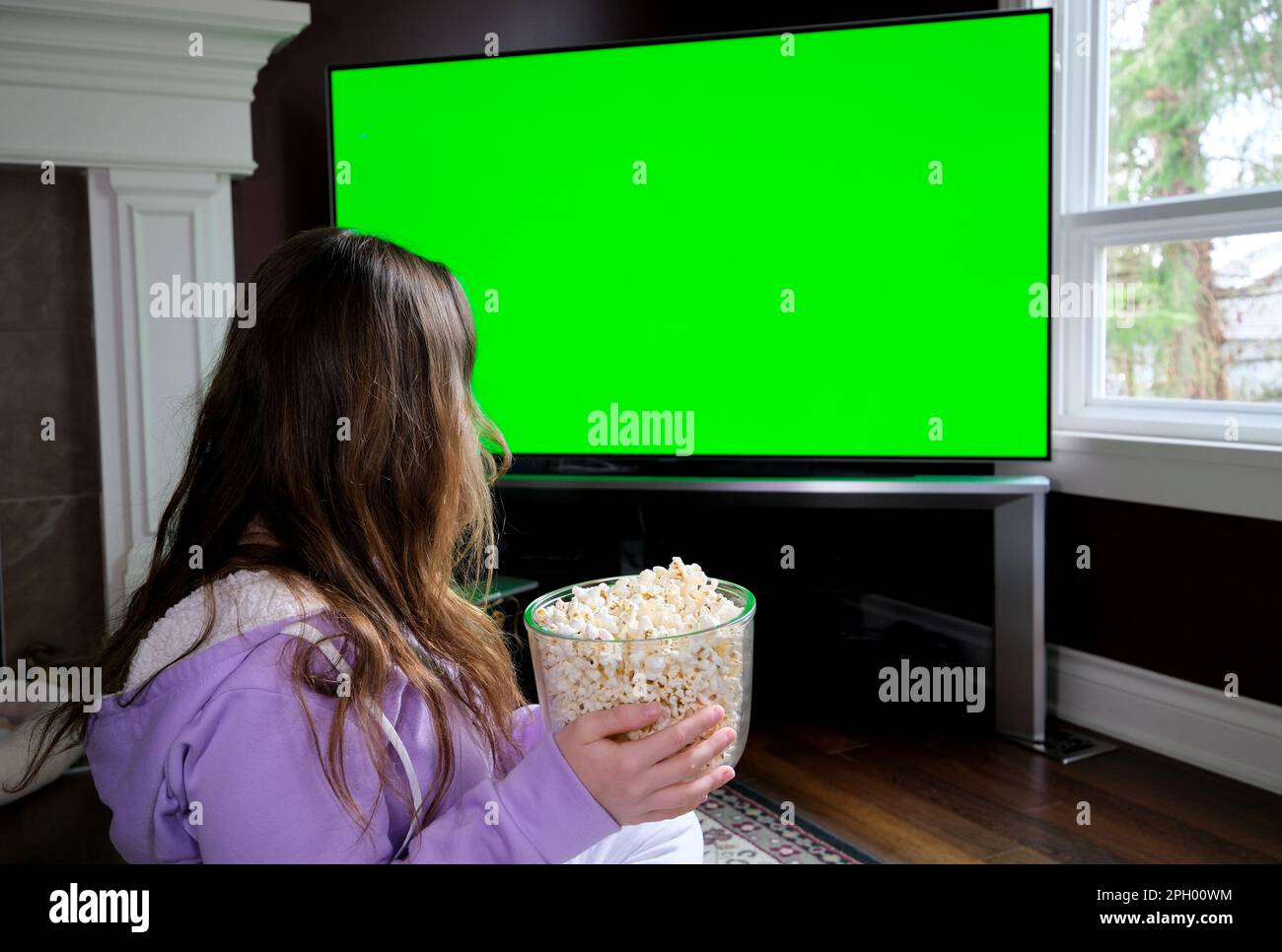 young woman watches projector, TV, movies with popcorn in evening large ...