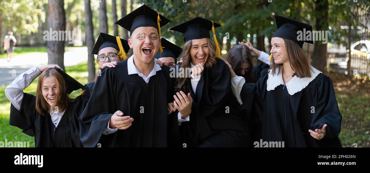A group of graduates in robes congratulate each other on their ...