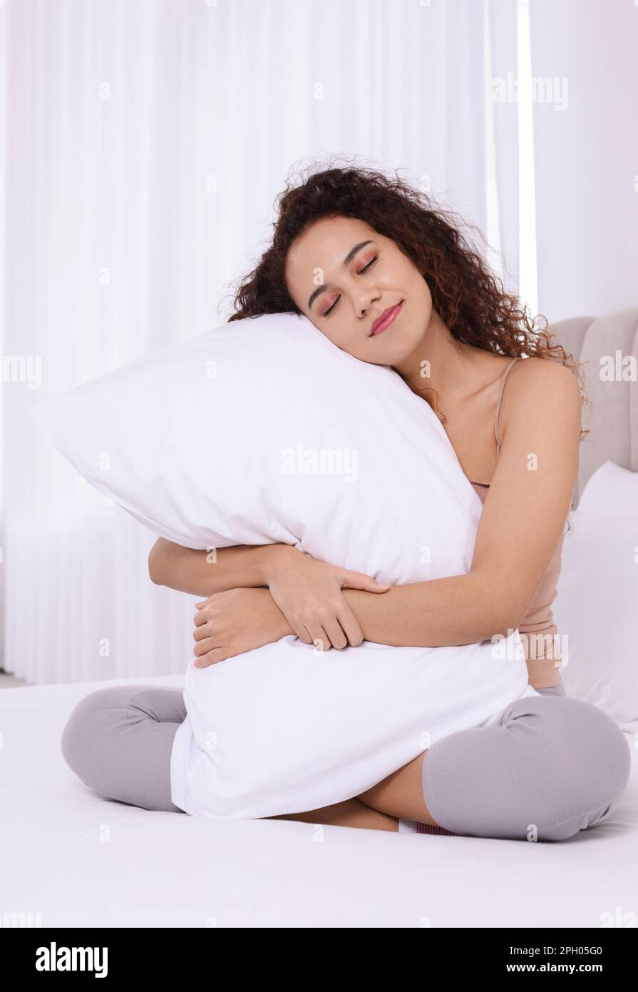 Happy African American woman hugging soft pillow on bed at home Stock ...