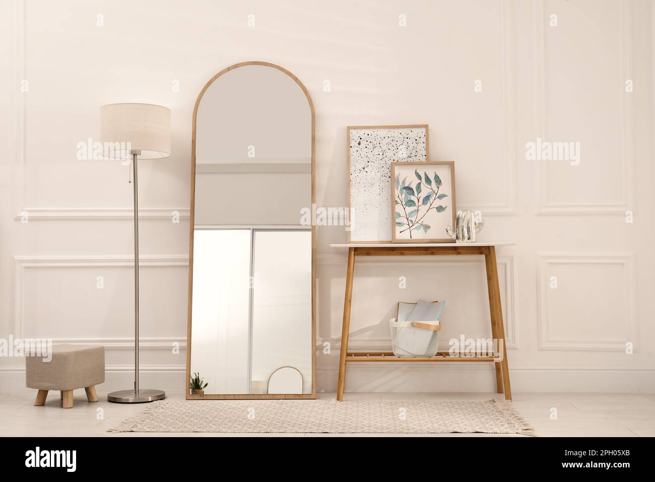 Beautiful mirror, console table and lamp near white wall indoors ...