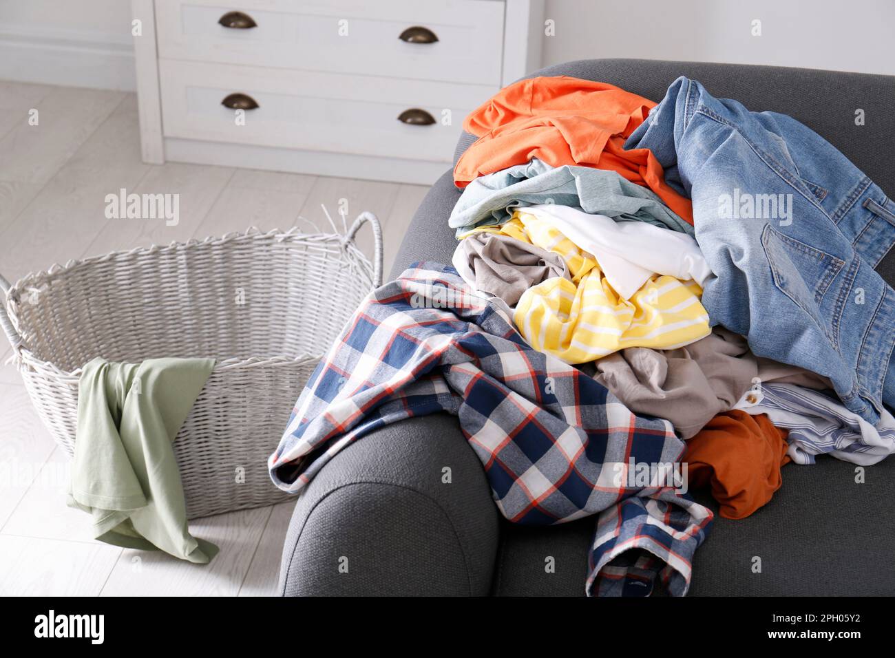 Messy pile of dirty clothes on sofa in living room. Tidying up method ...