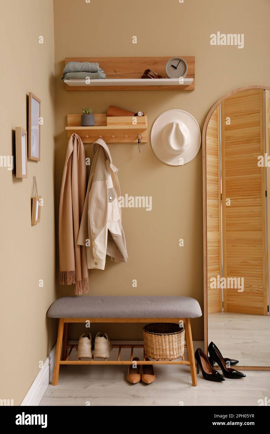 Hallway interior with stylish furniture, accessories and wooden hanger ...