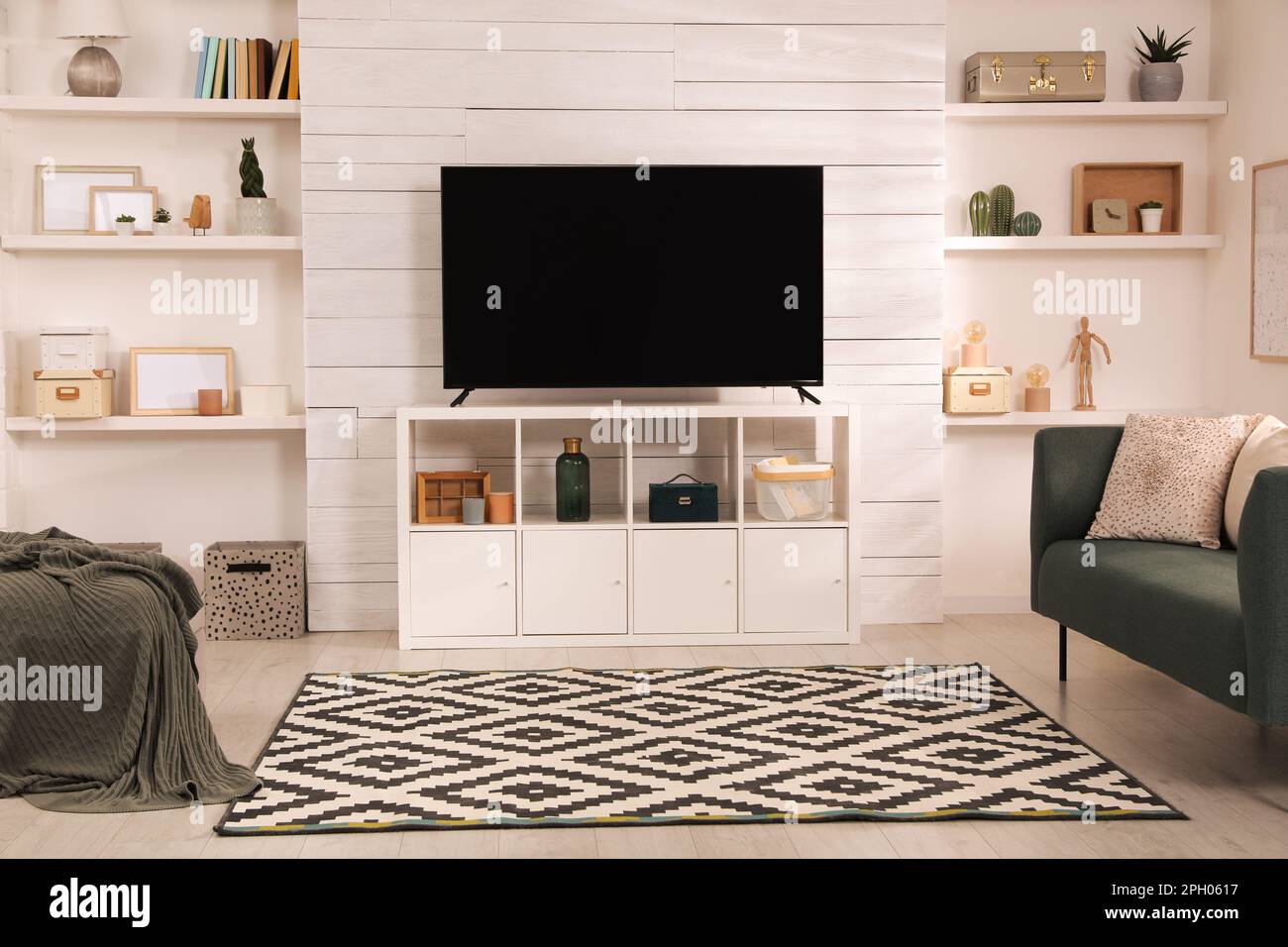 Modern TV on cabinet, comfortable sofa and decor elements in living ...
